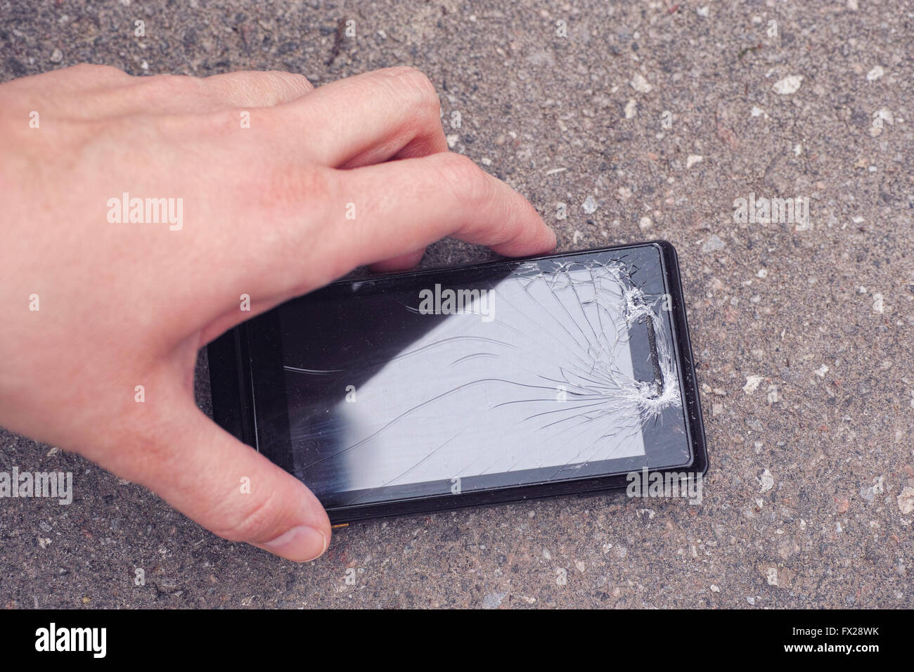 Person picking up a cracked smartphone. Smartphone with cracked screen ...