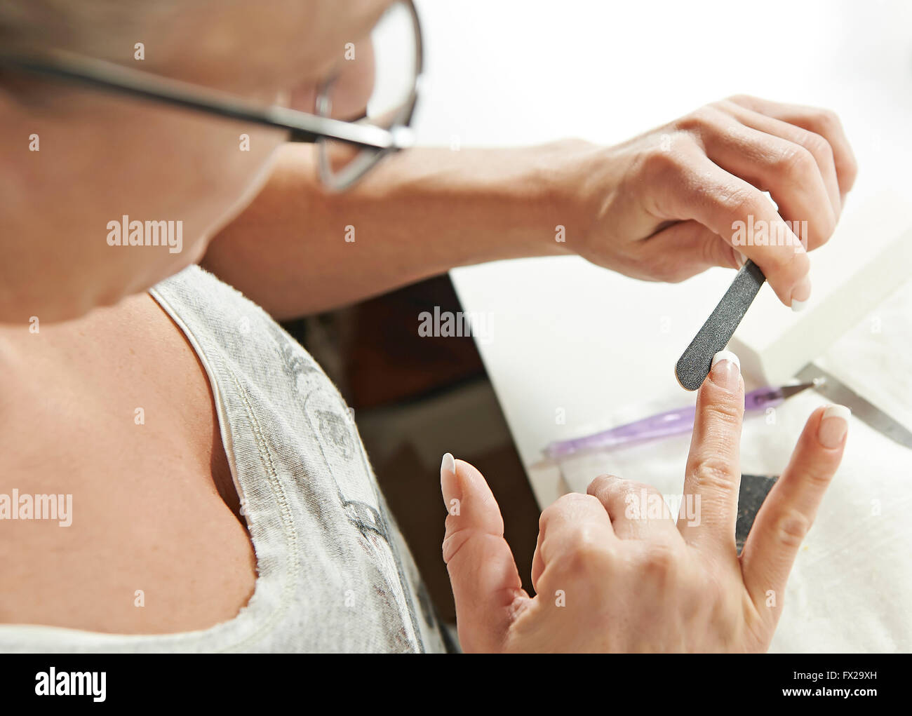 A woman with glasses filing her nails Stock Photo - Alamy