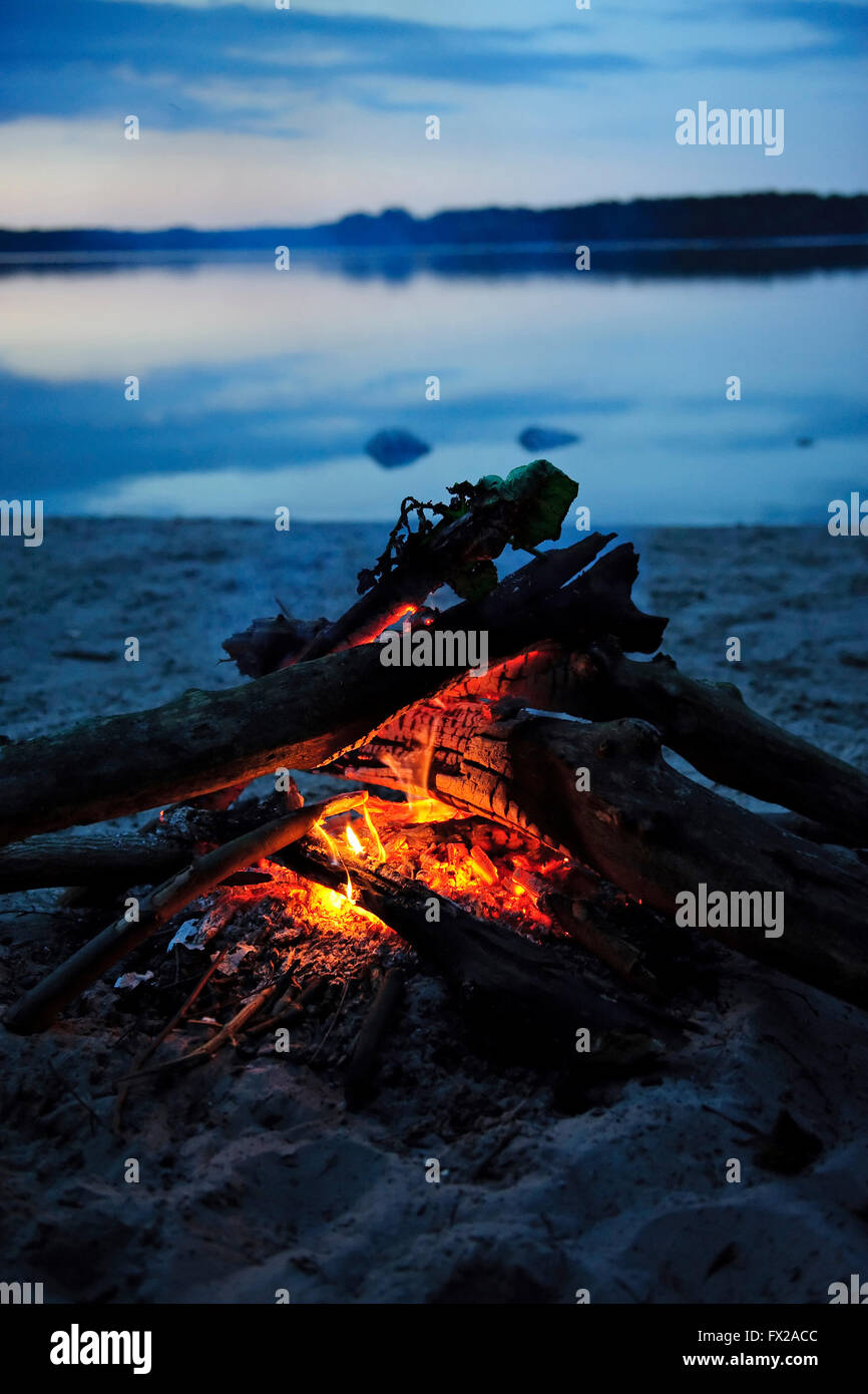 Lake shore bunfire in the twilight Stock Photo - Alamy
