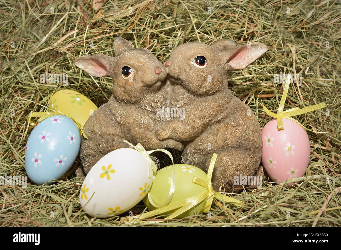Easter bunnies siiting in hay with colourful eggs around them Stock ...