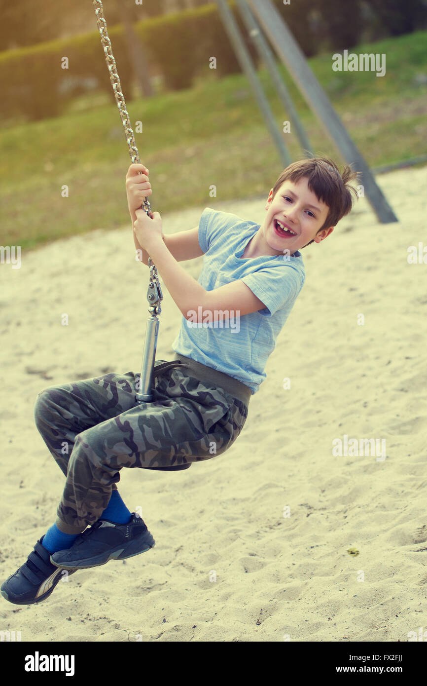 Little boy hanging on swing rope outdoor in park Stock Photo - Alamy