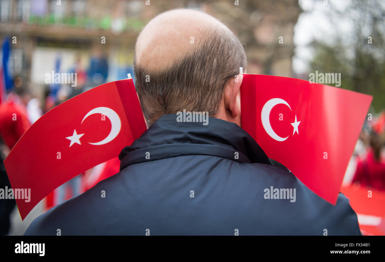 Munich, Germany. 10th Apr, 2016. A man carrying two Turkish national ...