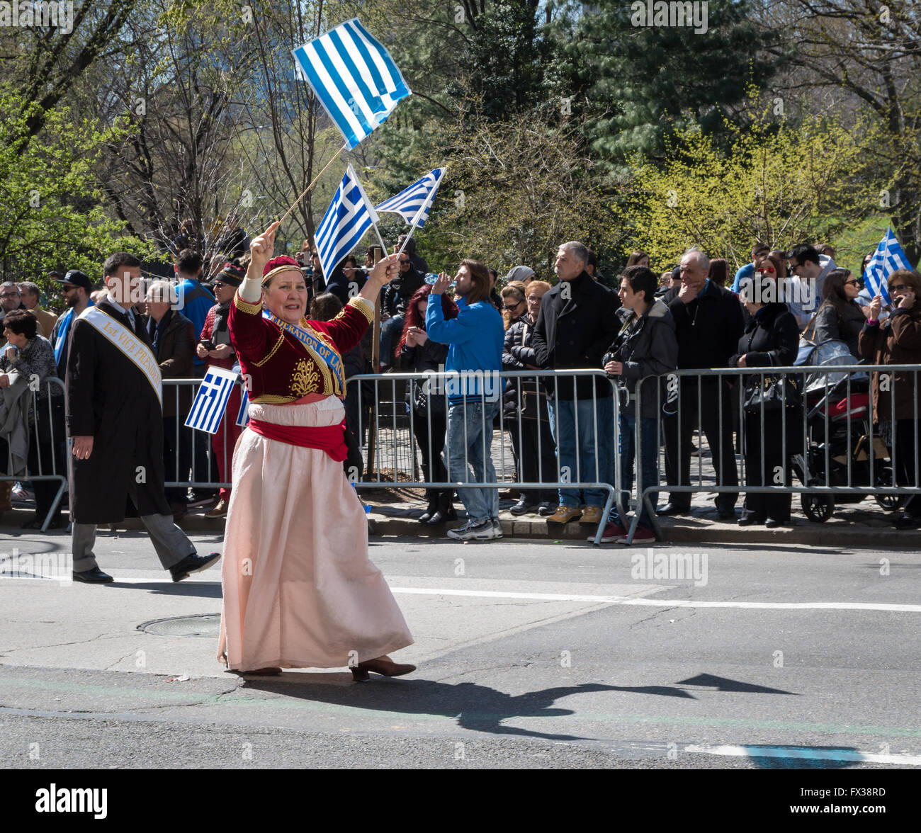 Woman wearing traditional Greek dress marching and waving flags in the ...