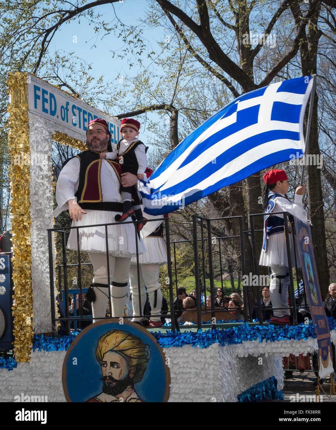 Man carrying his son both in traditional Greek costume on a float in ...
