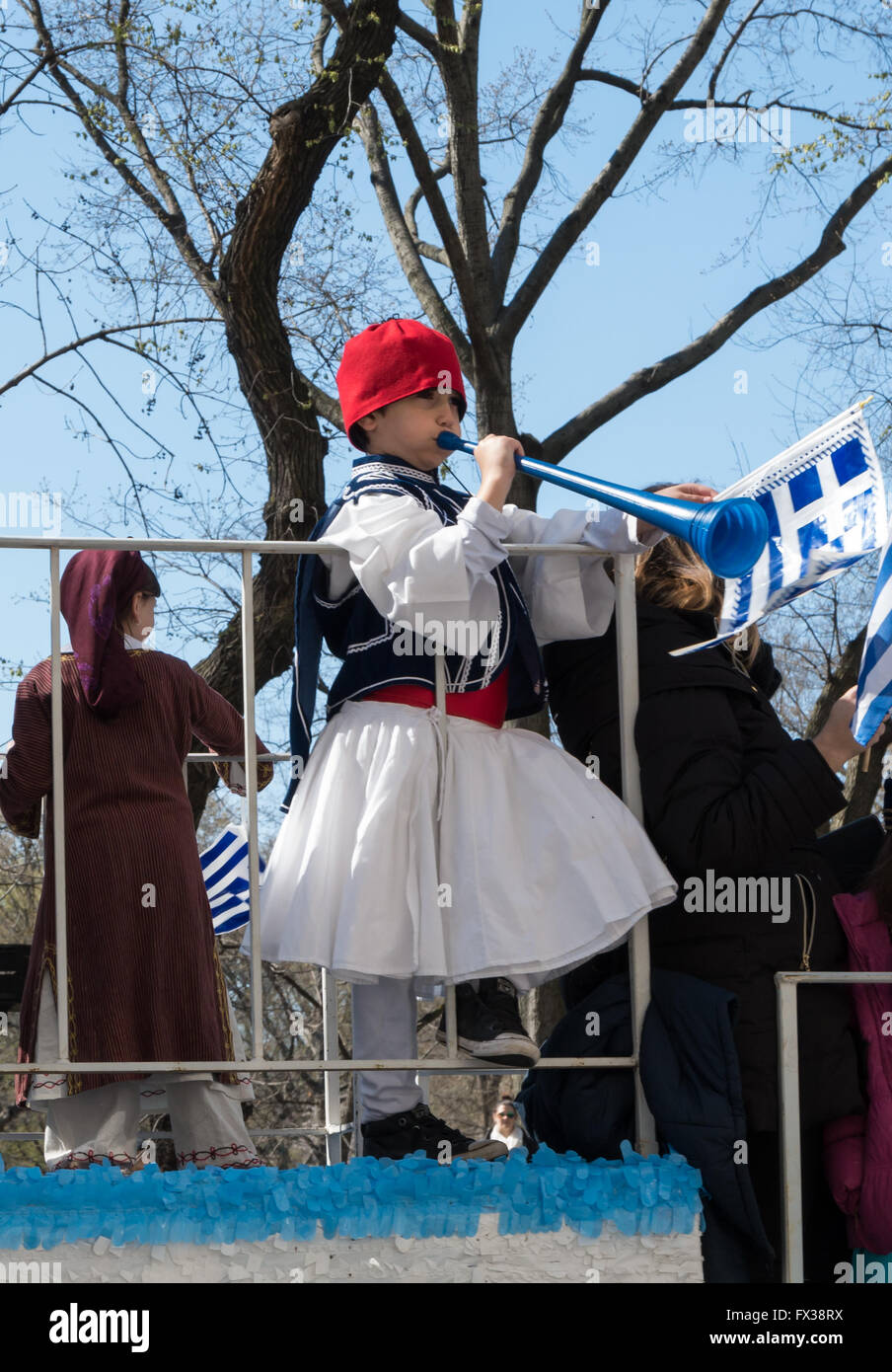 Little boy in traditional Greek costume blowing on a vuvuzela horn on a ...
