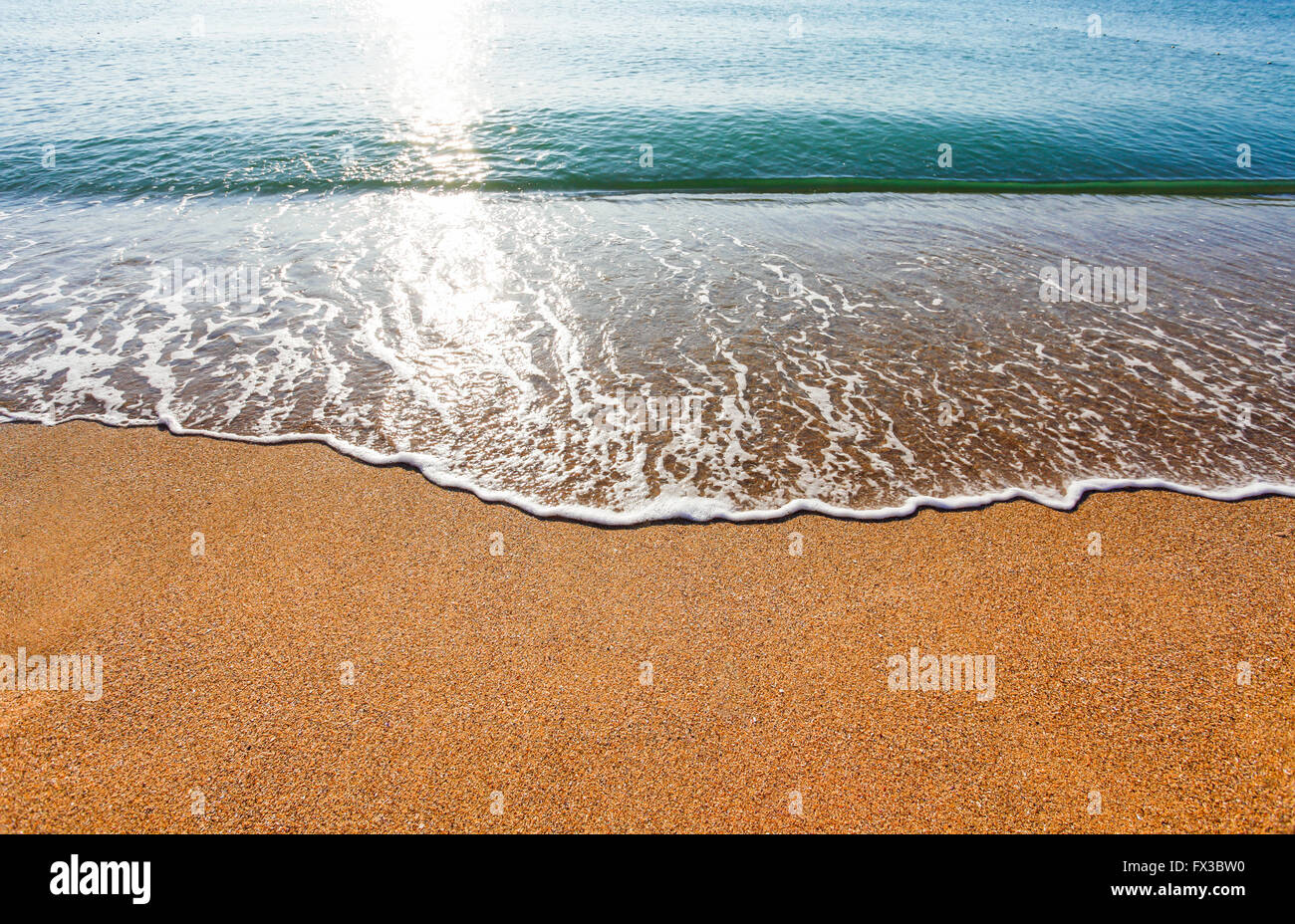 Sun light reflected on soft wave on the sandy beach Stock Photo - Alamy