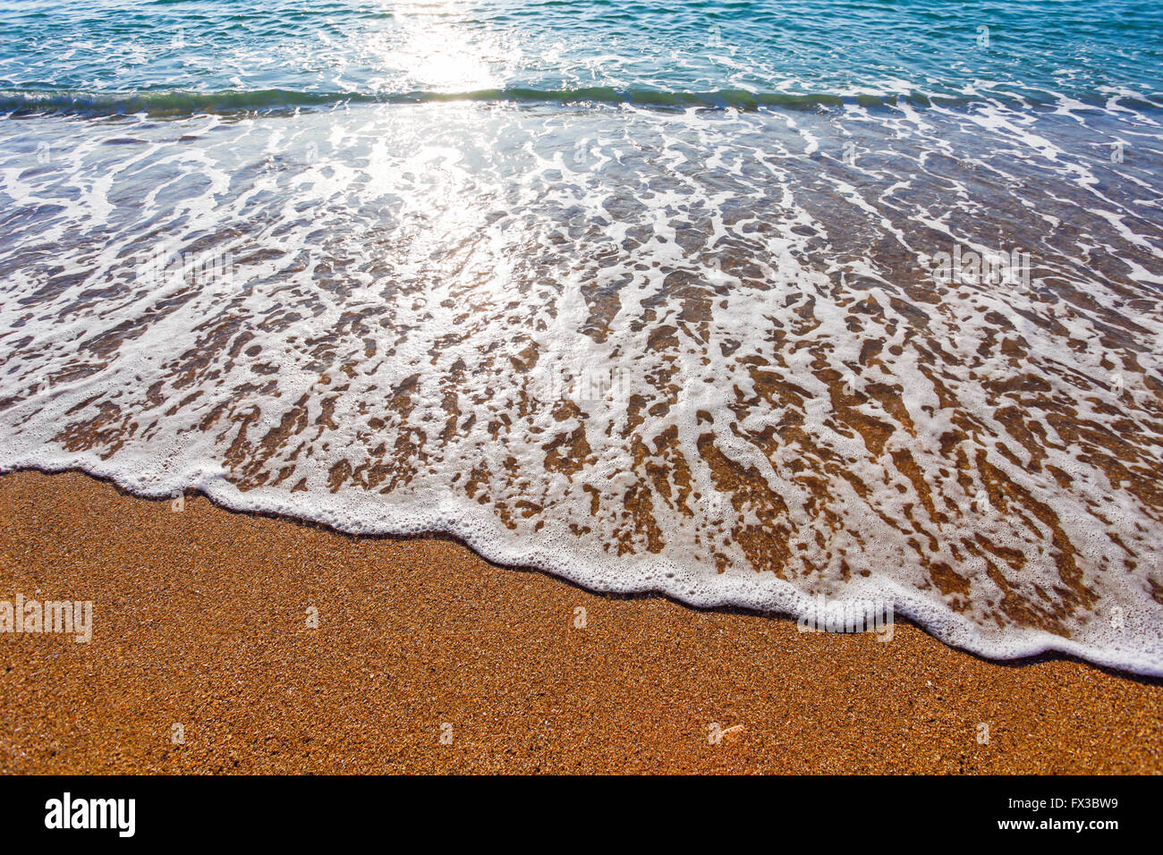 Sun light reflected on soft wave on the sandy beach Stock Photo - Alamy