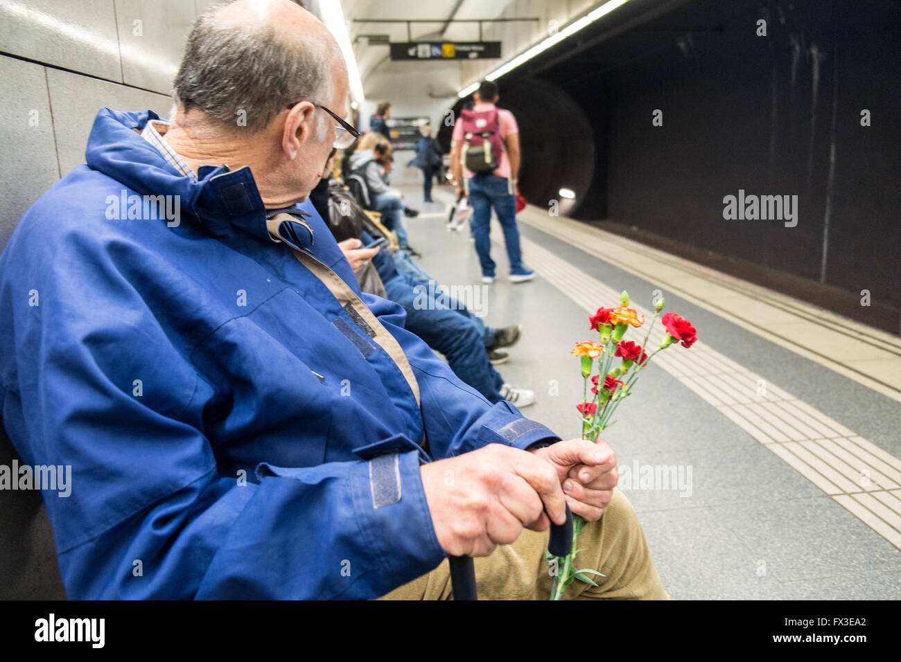 Elderly,mature man waiting for train while holding a bunch of flowers ...