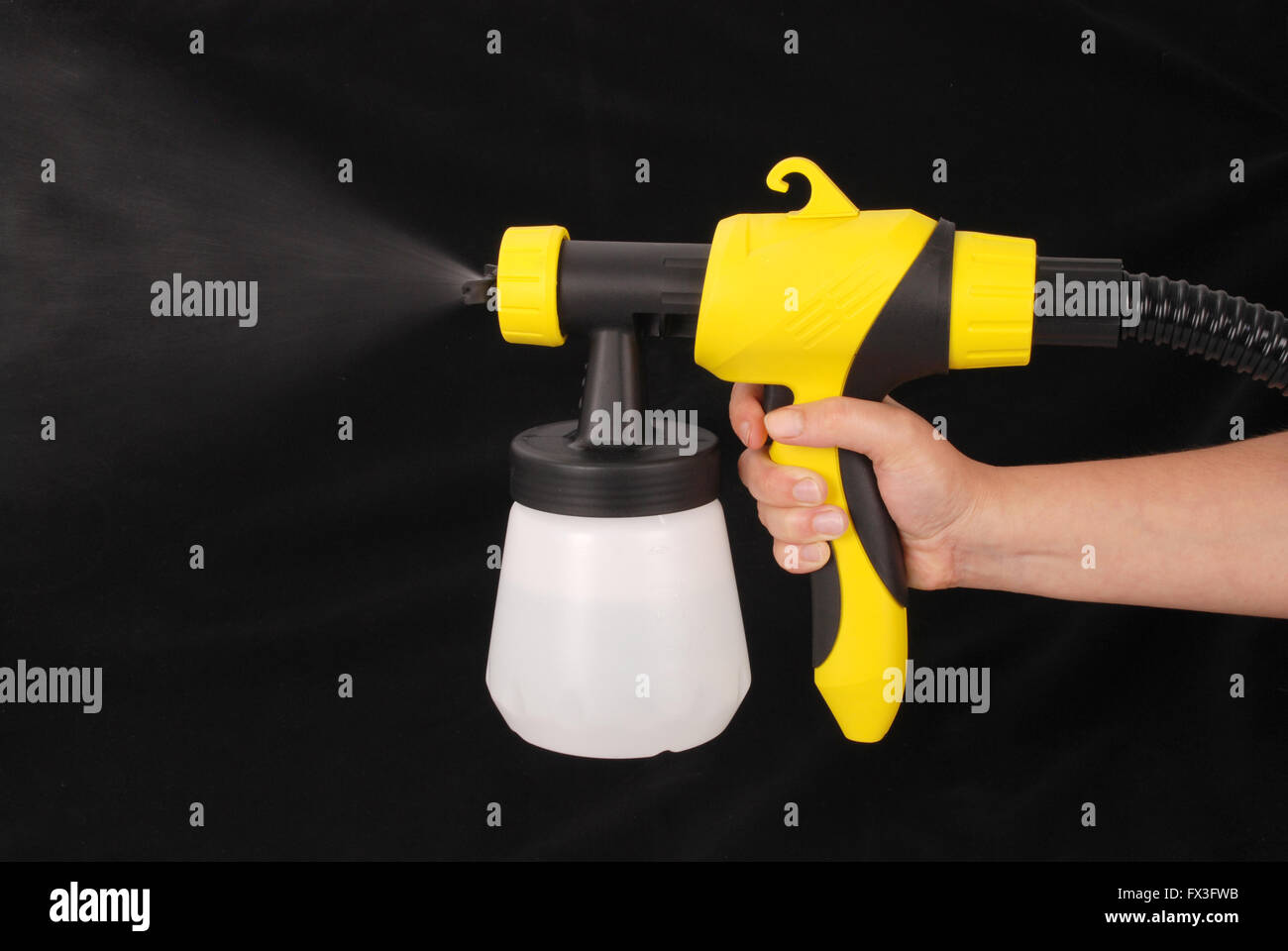 Spray gun in hand on dark background Stock Photo - Alamy