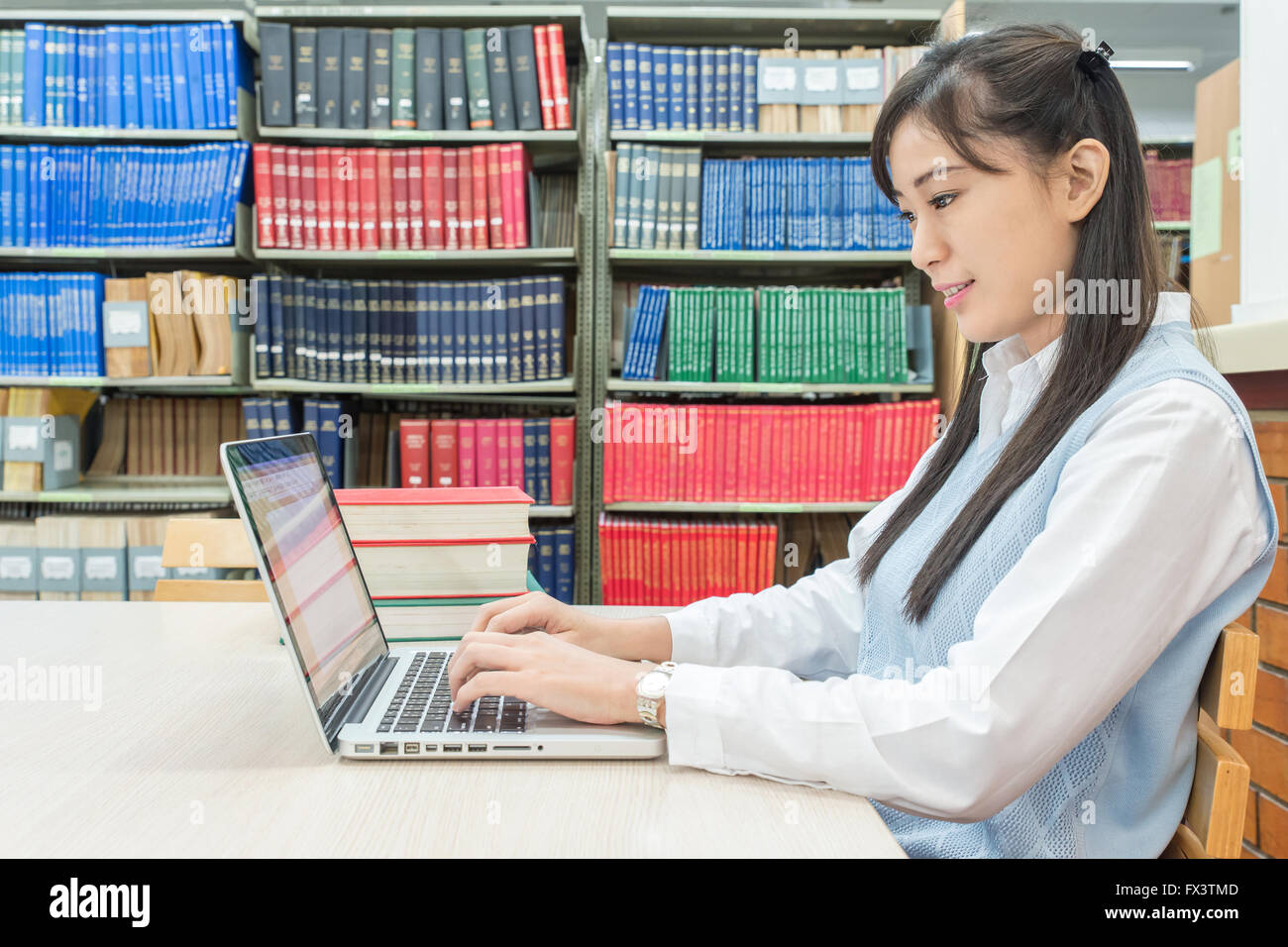 Asian female student with laptop and books working in a high school ...