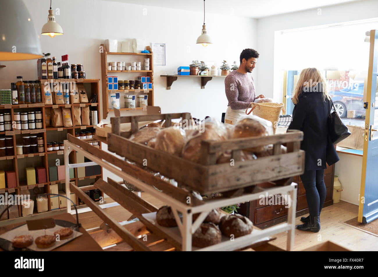 Male Sales Assistant Serving Female Customer In Delicatessen Stock ...
