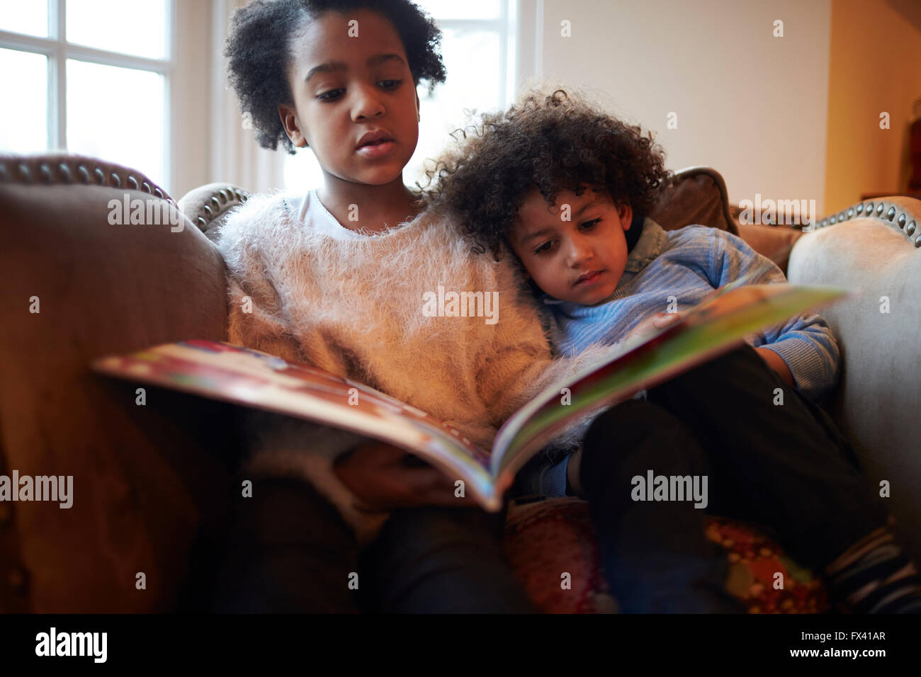 Brother And Sister Reading Book On Sofa Together Stock Photo - Alamy