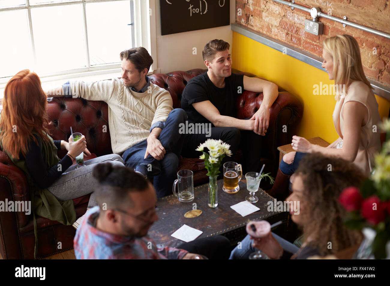 Group Of Friends Enjoying Drink In Bar Sitting On Sofa Stock Photo - Alamy
