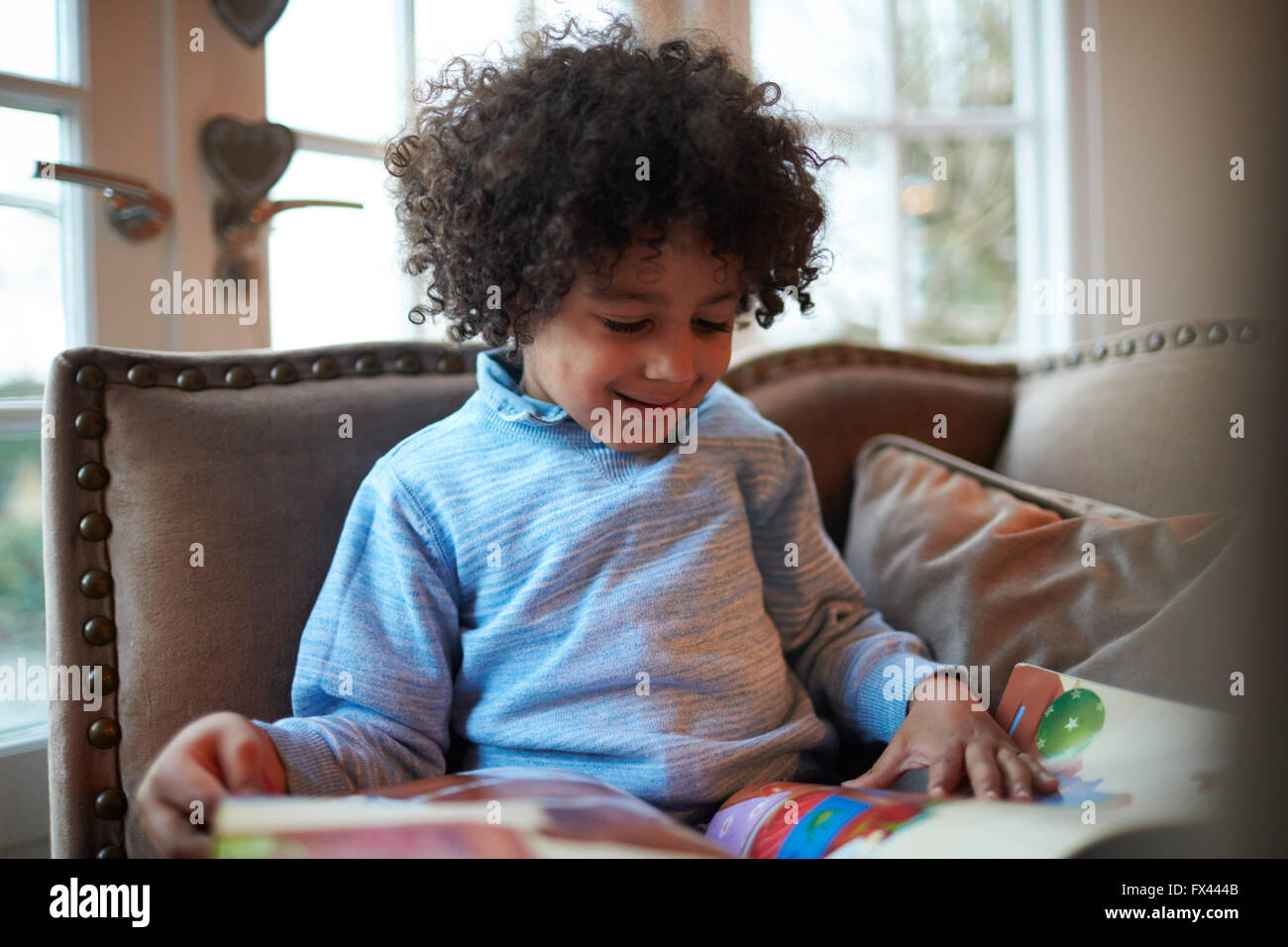 Young Boy Reading Book On Sofa At Home Stock Photo - Alamy