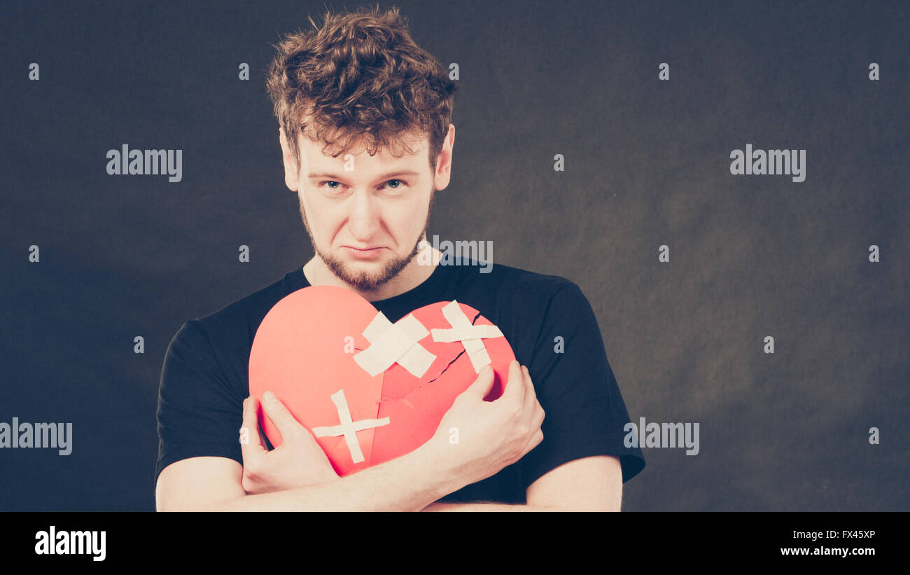 Heart broken concept. Unhappy sad man guy holding glued on love sign ...
