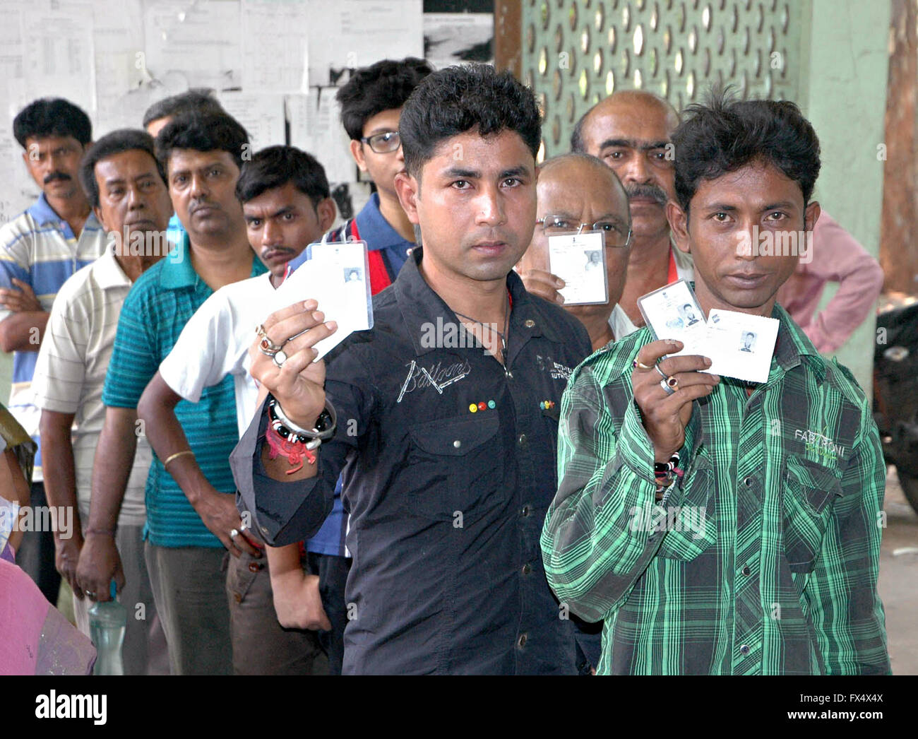 Voters show their voter identification as they stand in a queue to cast ...