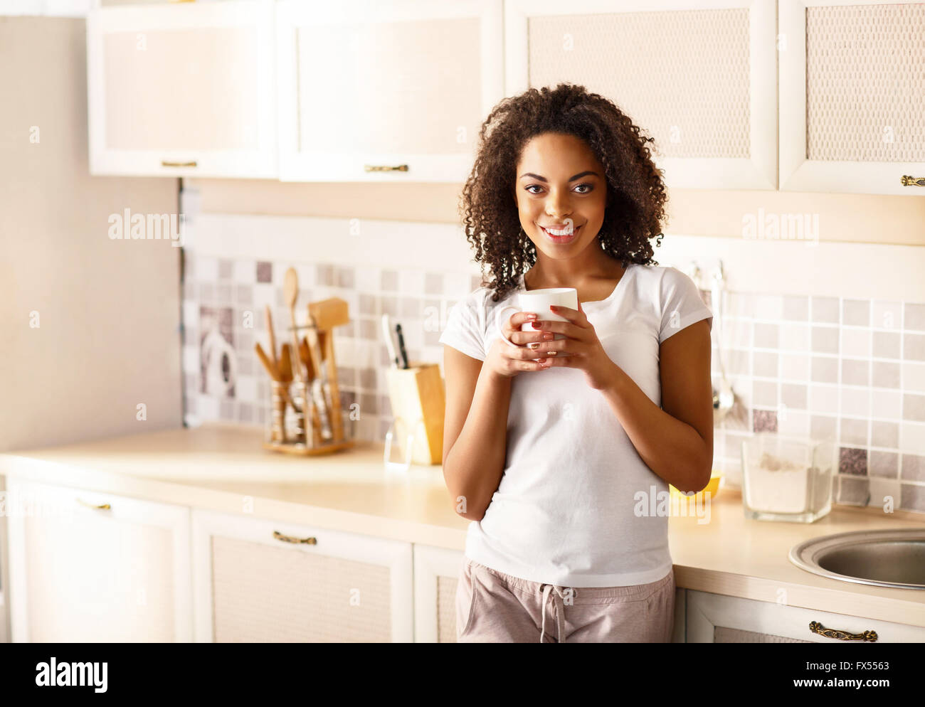 Pleasant girl drinking tea in the kitchen Stock Photo - Alamy