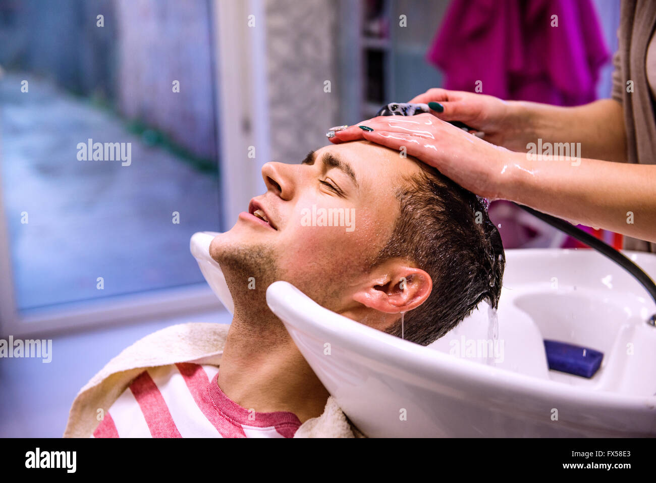 Professional hairdresser washing hair to her handsome client Stock ...