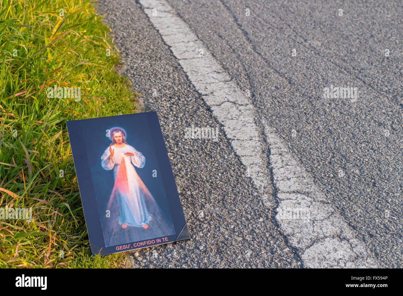 the Merciful Jesus iconon dirt asphalt road, italian sentence written ...