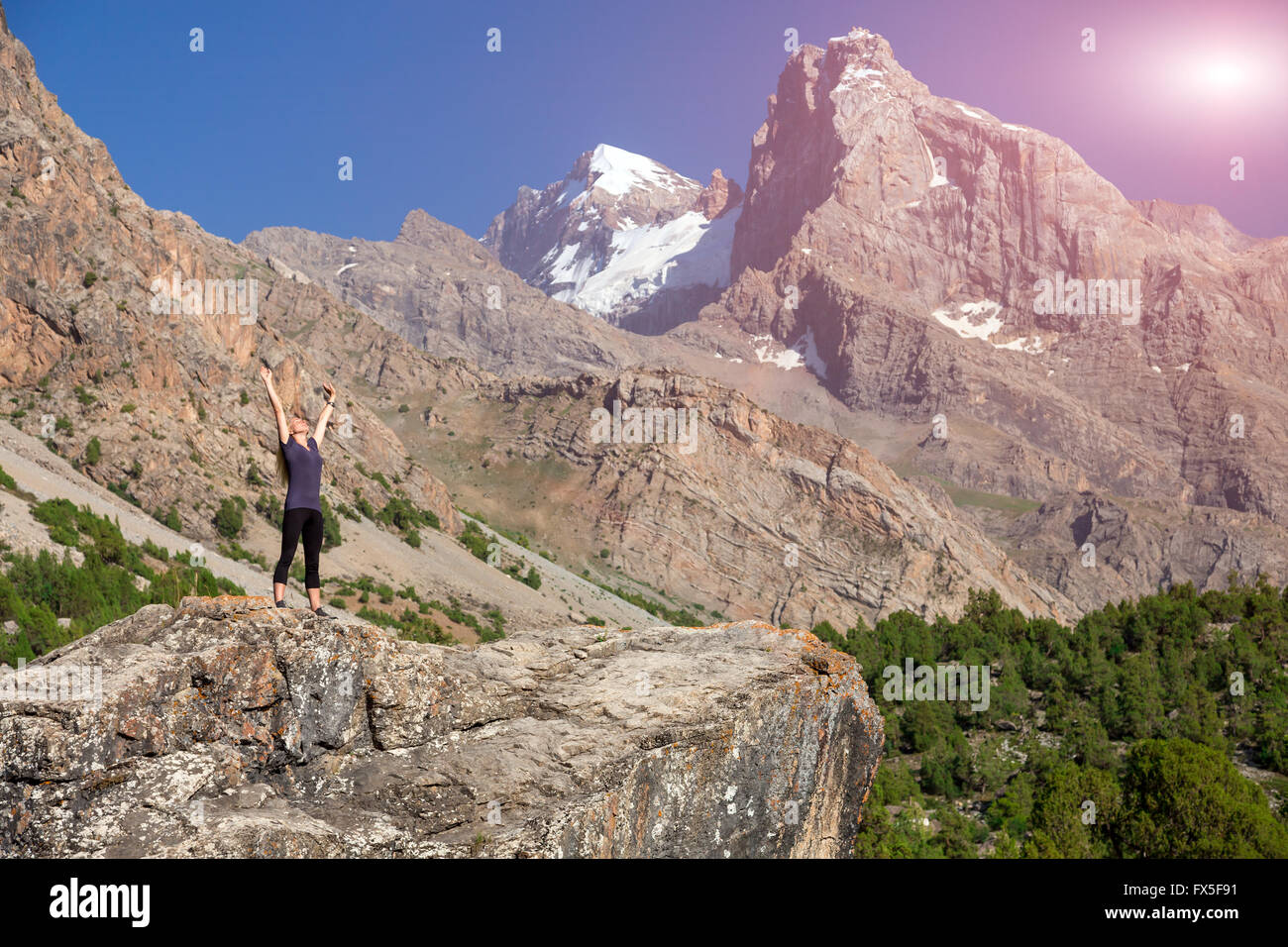 Young Woman Staying on Rock with Arms Raised Up Stock Photo - Alamy
