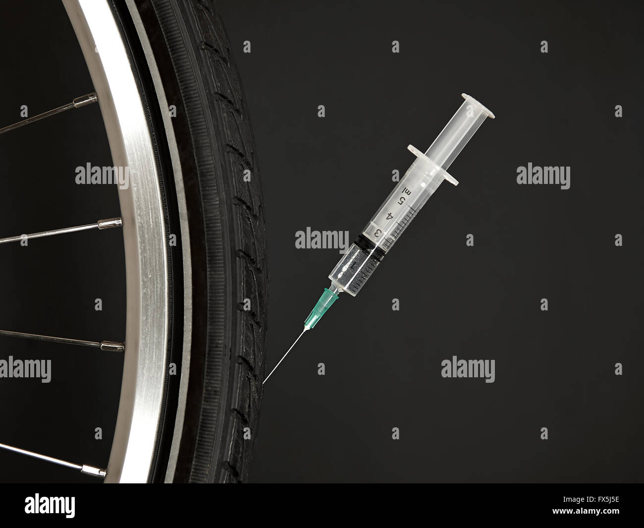 Bicycle wheel with a syringe in it illustrating doping Stock Photo - Alamy