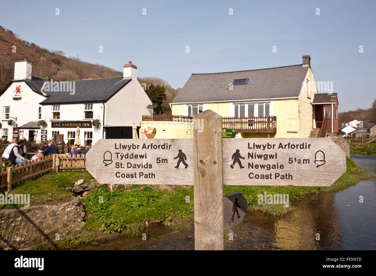Signpost next to "Harbour Inn" pub on a sunny day in Solva, an ...