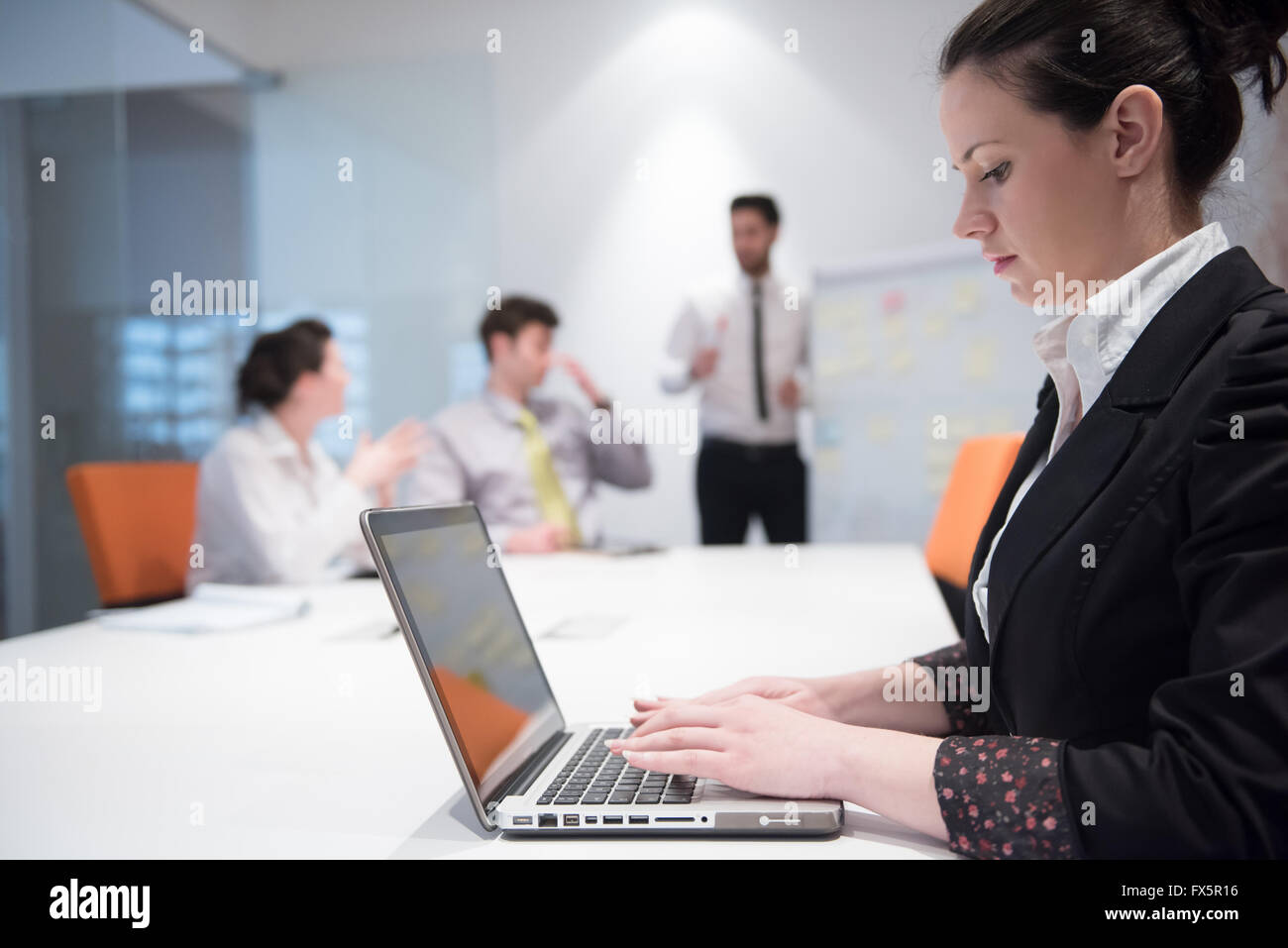 young business woman on meeting usineg laptop computer, blured group of ...