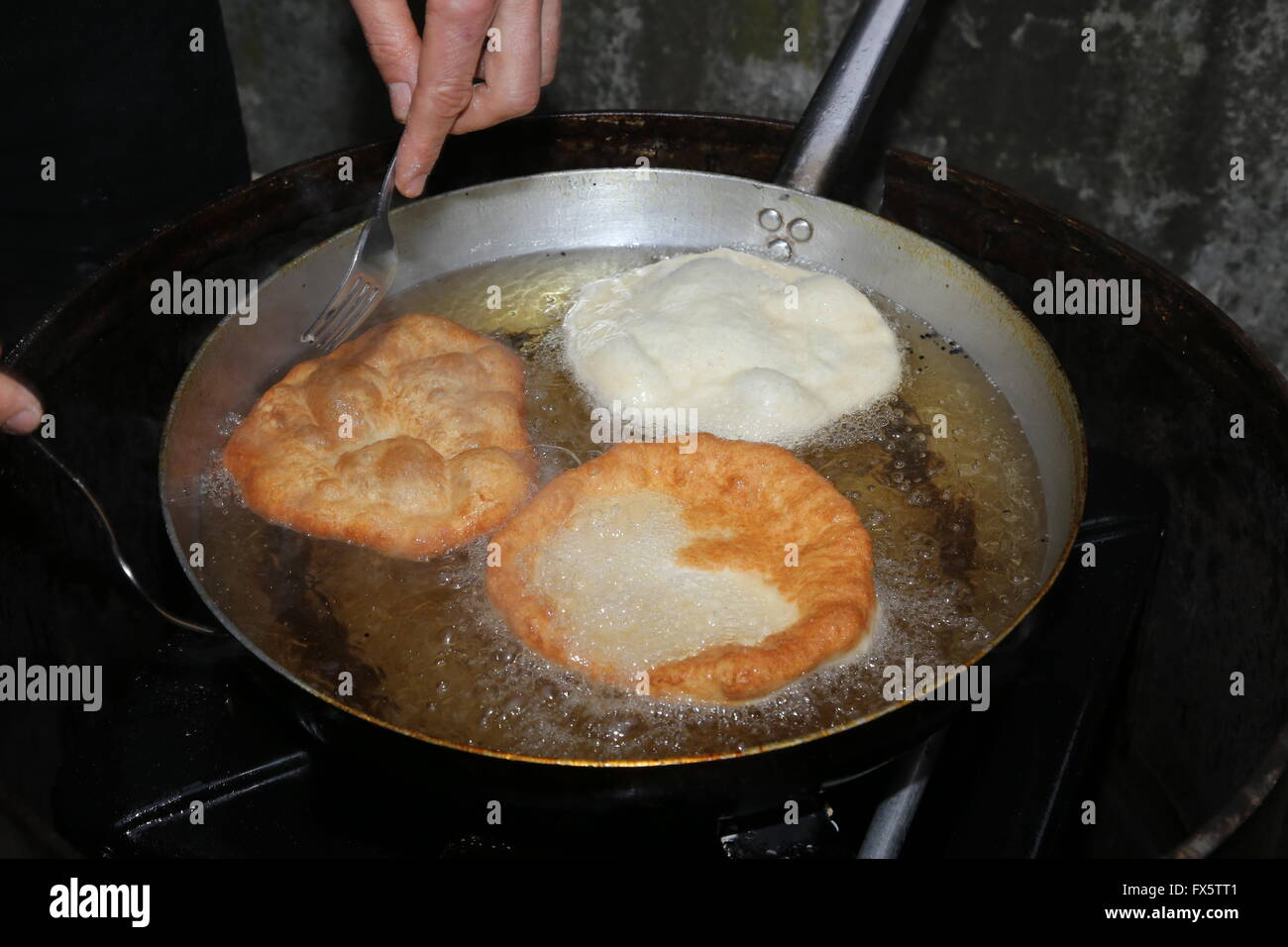 Cook hands while cooking the big fried fritters dipped in boiling oil ...