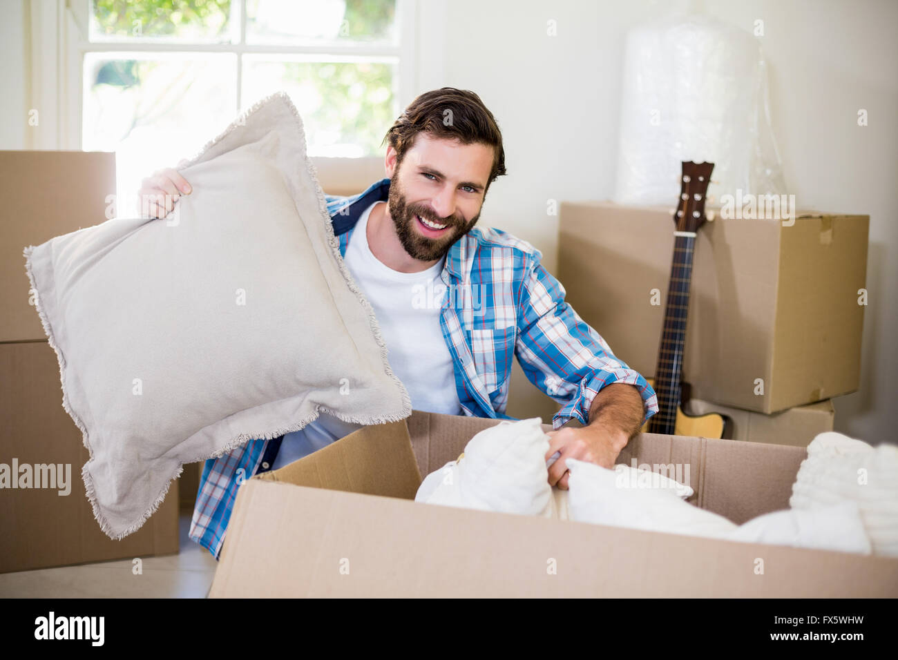 Portrait of young man unpacking carton boxes Stock Photo - Alamy