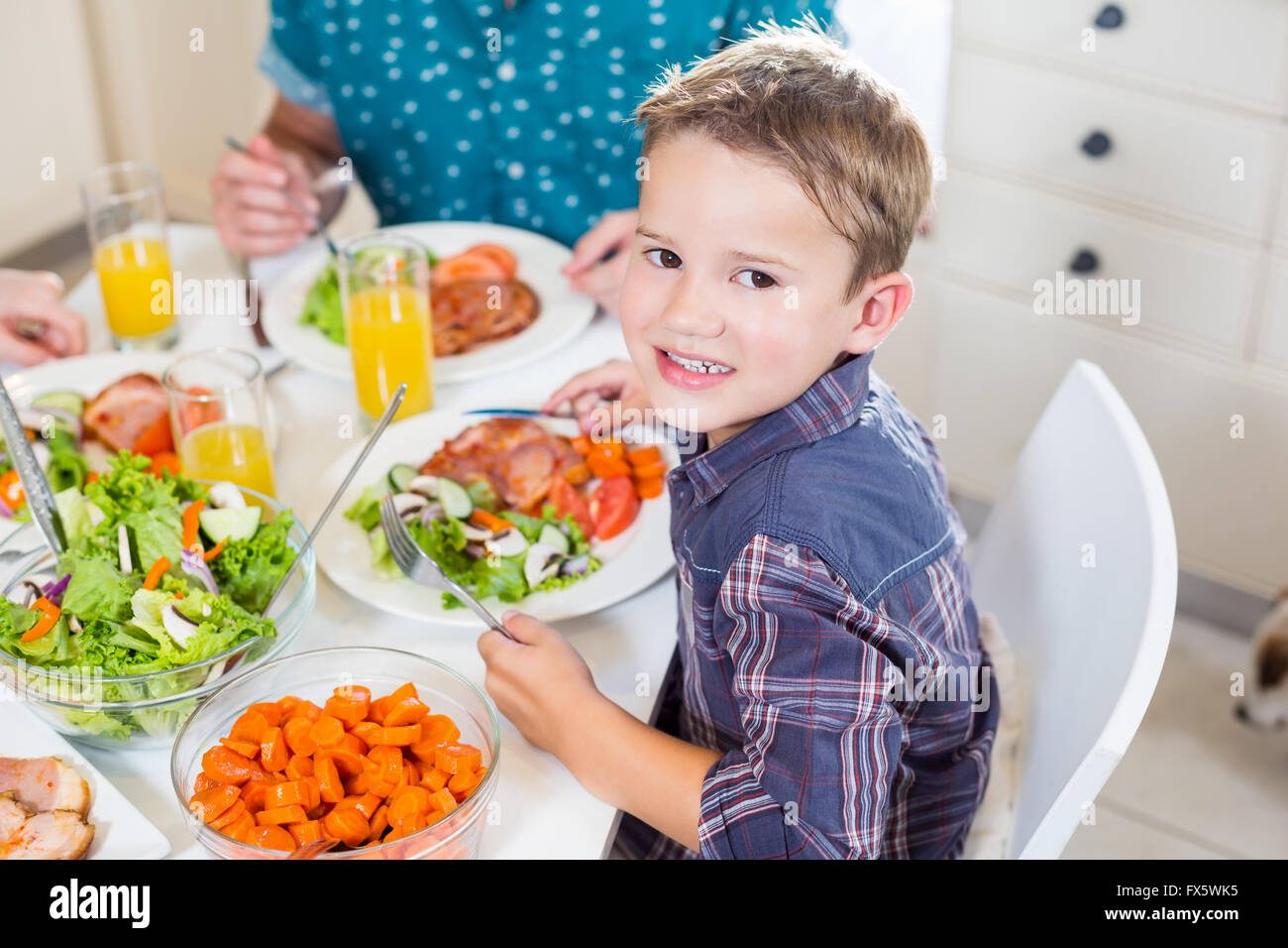 Boy sitting at dining table smiling Stock Photo - Alamy