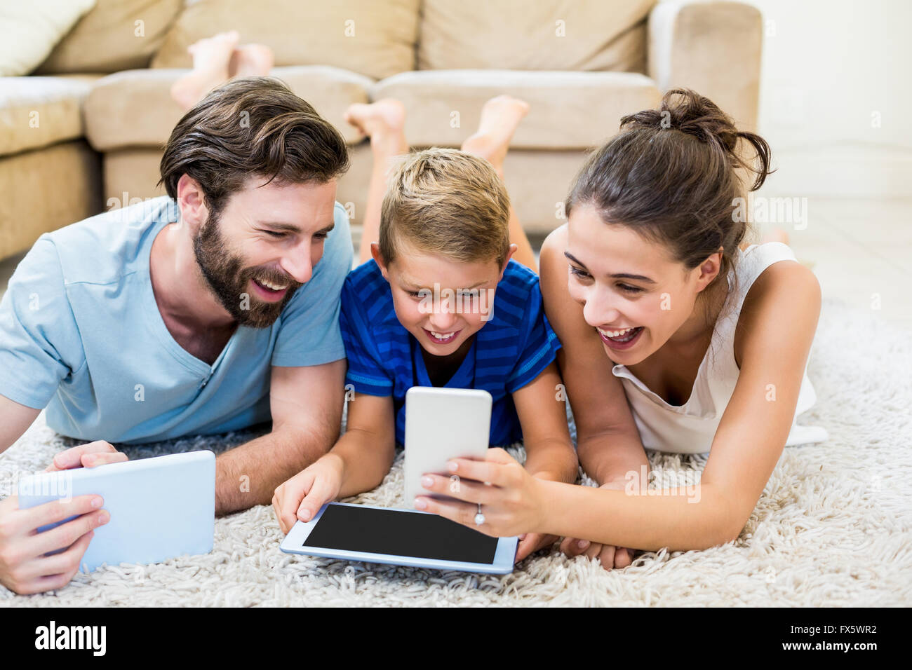 Parents using digital tablet and mobile phone in living room Stock ...