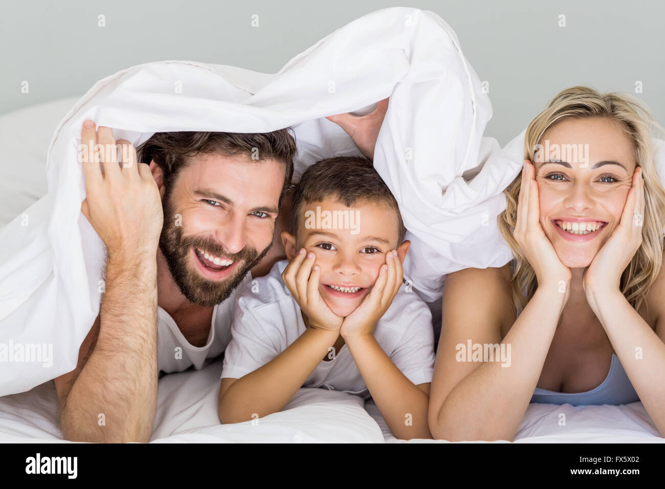 Portrait of parents and son lying on bed in bedroom Stock Photo - Alamy