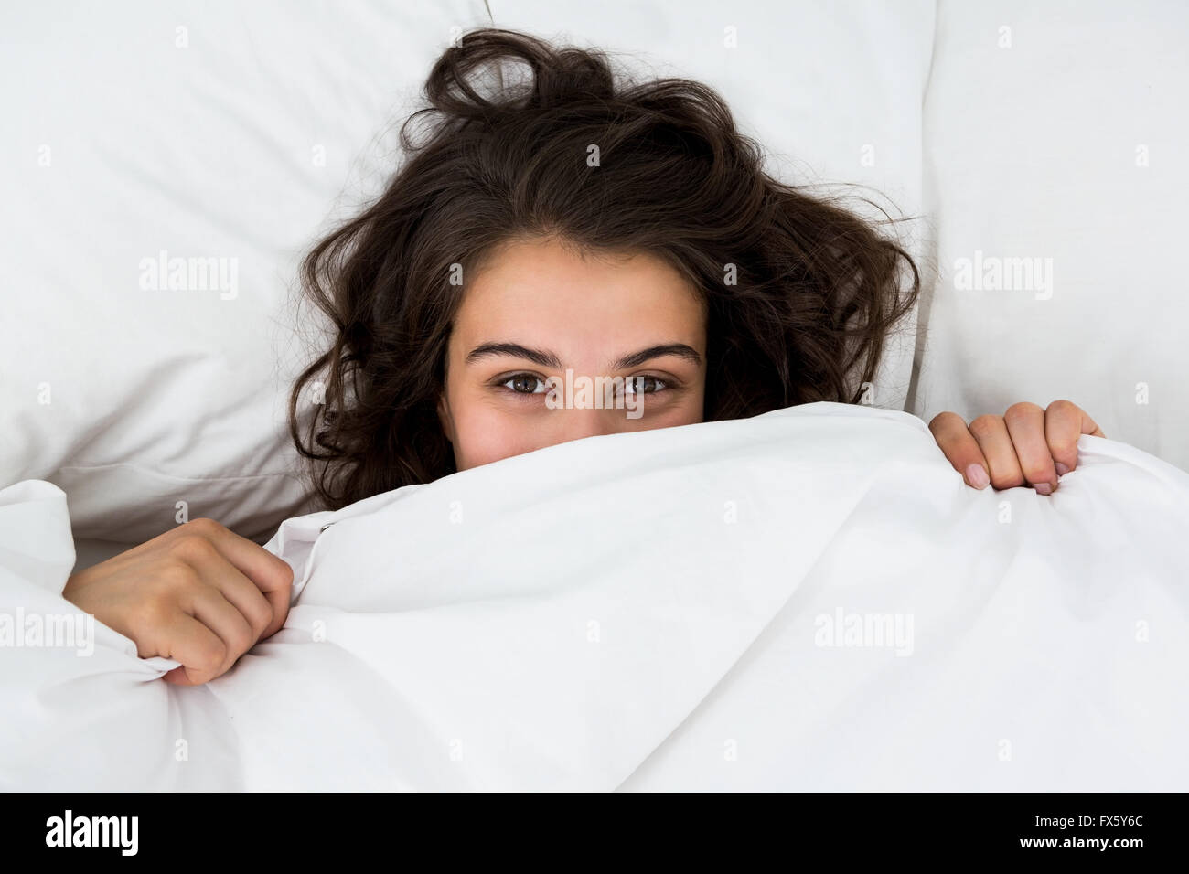 Woman hiding under blanket on bed Stock Photo - Alamy