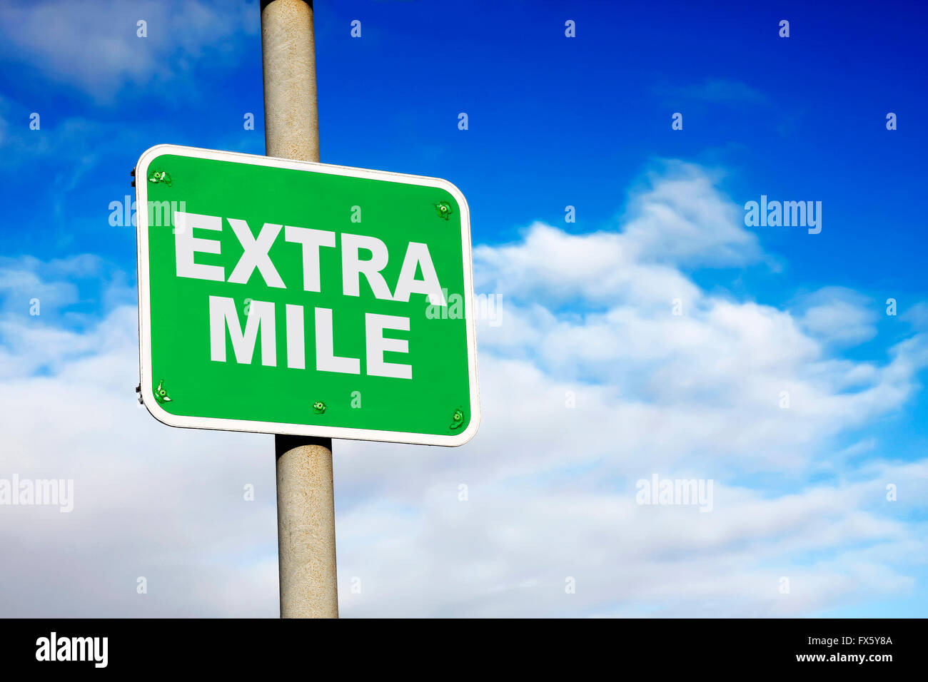 Green extra mile sign against a blue sky Stock Photo - Alamy