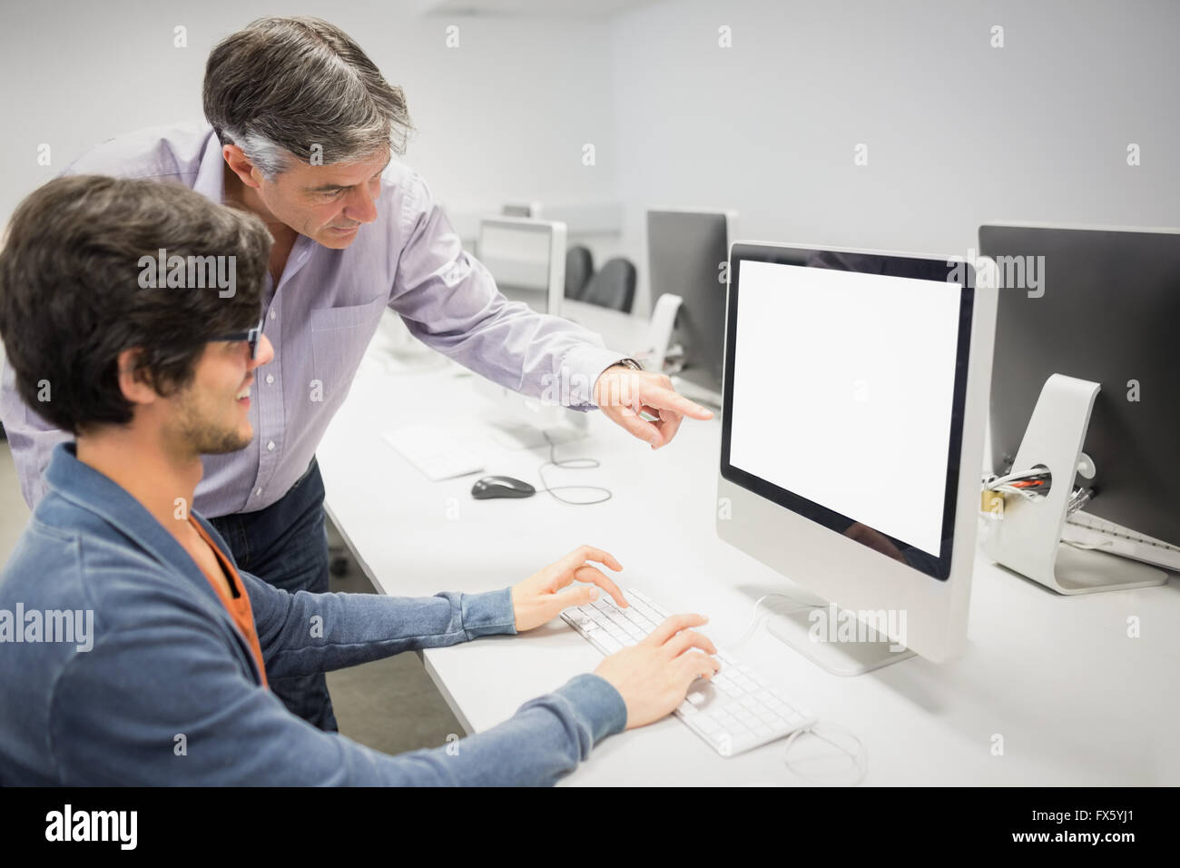 Computer teacher assisting a student Stock Photo - Alamy