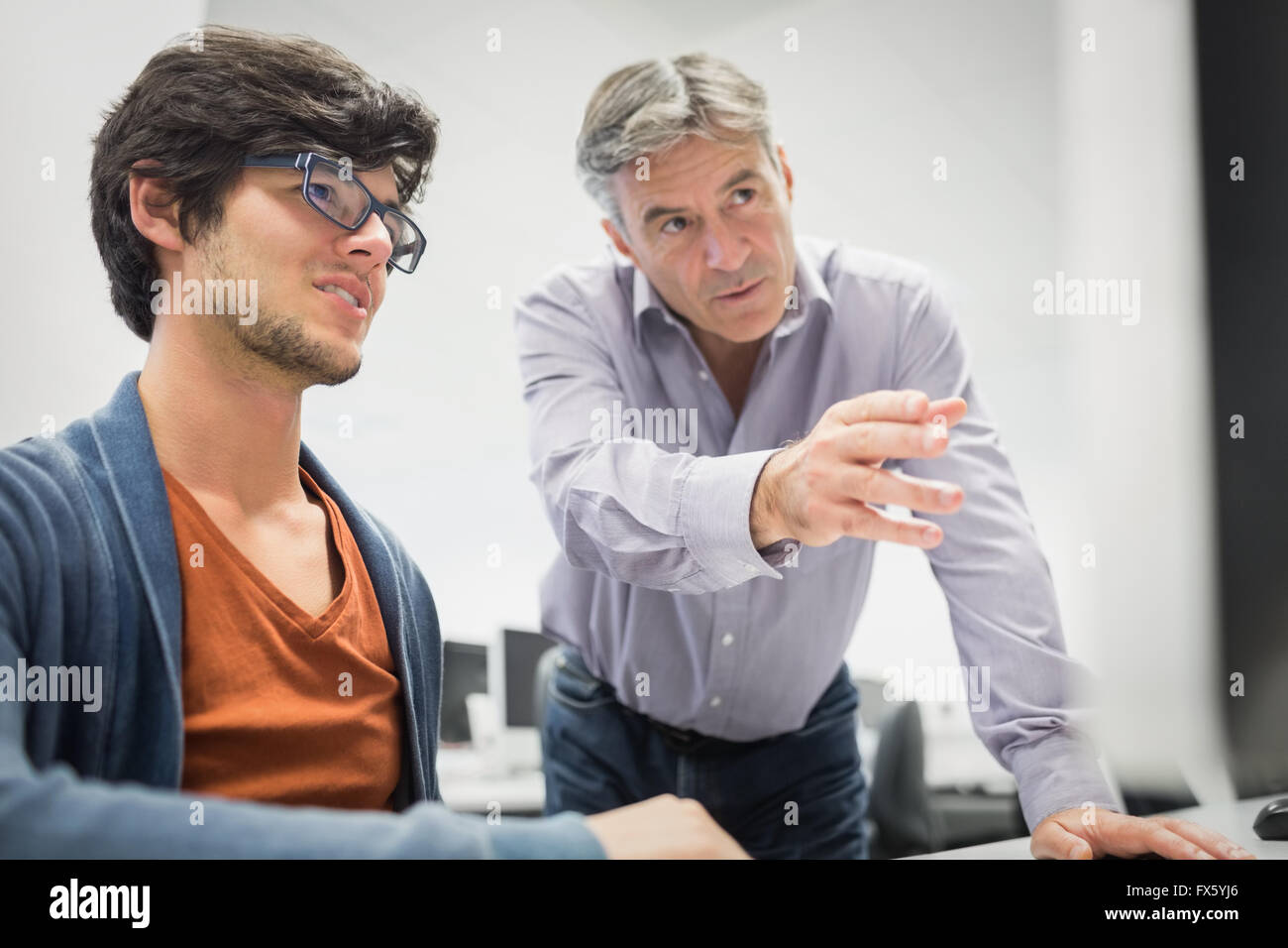 Computer teacher assisting a student Stock Photo - Alamy