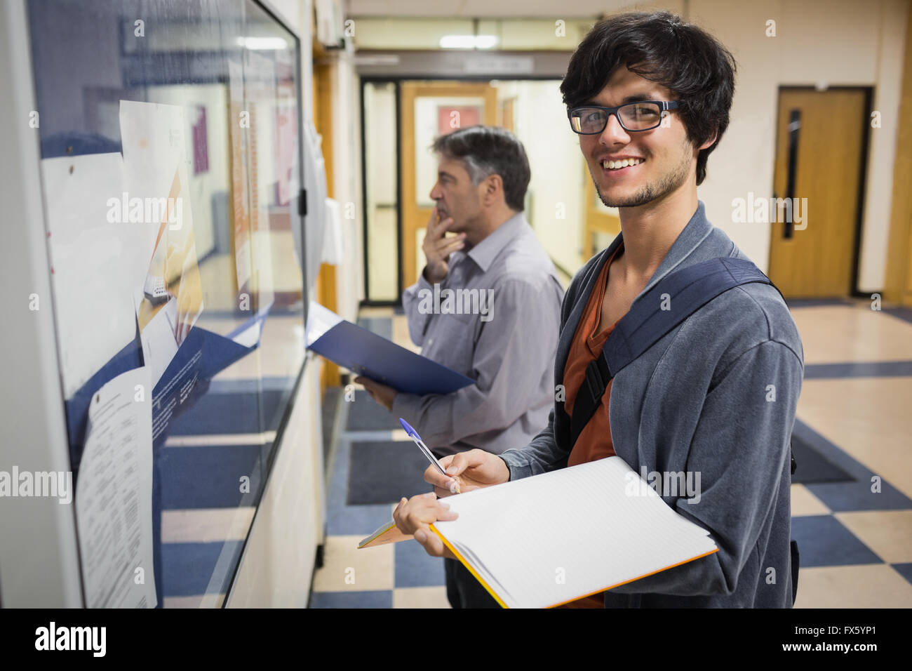 Portrait of smiling student standing in front of notice board Stock ...