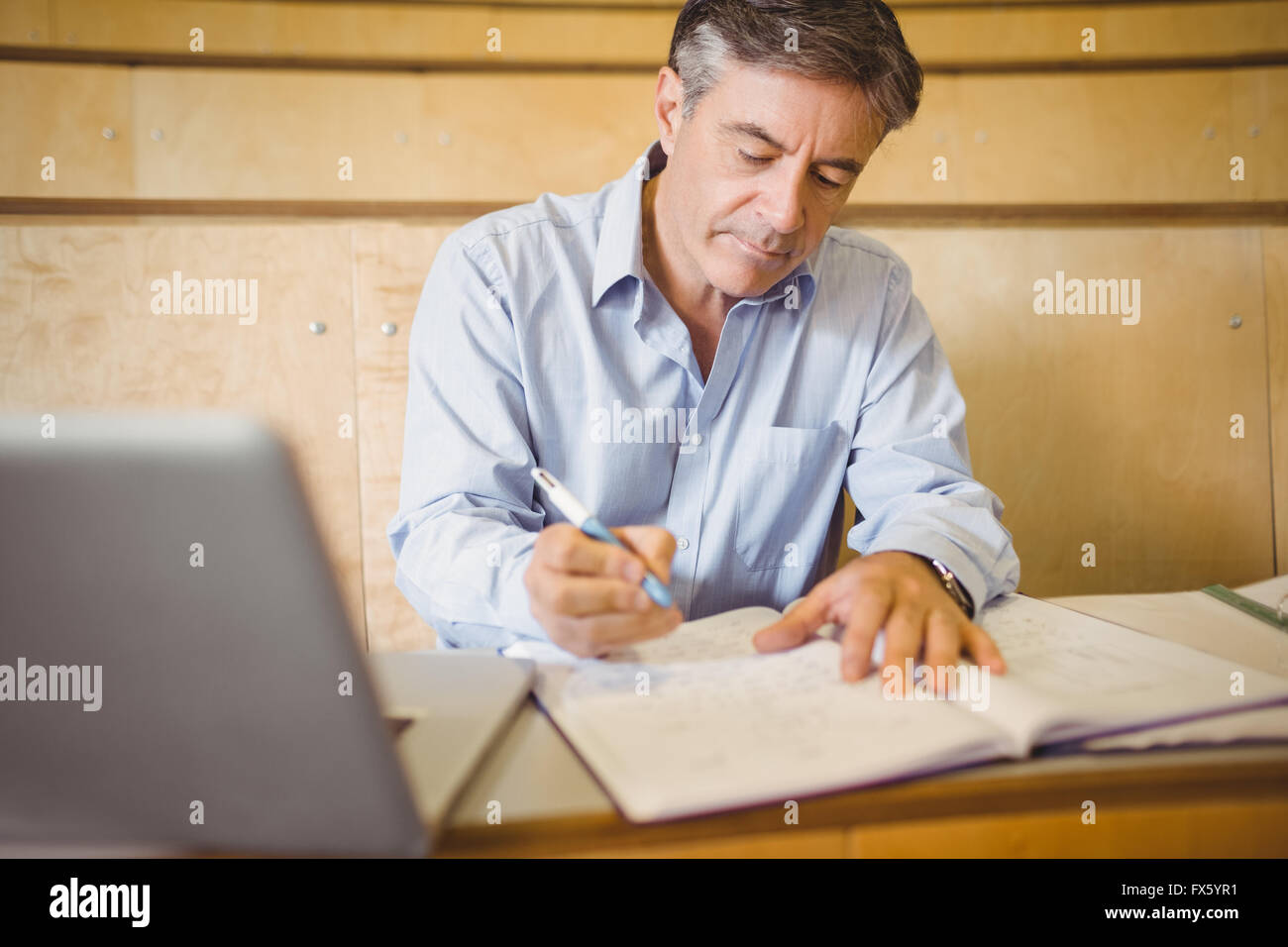 Professor writing in book at desk Stock Photo - Alamy