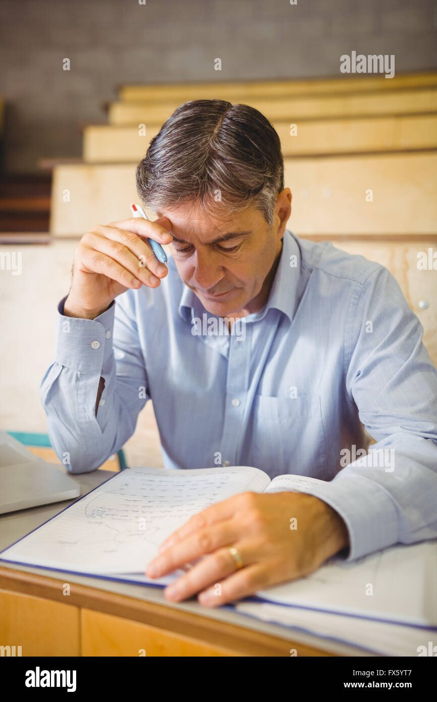 Professor sitting at desk and reading book Stock Photo - Alamy