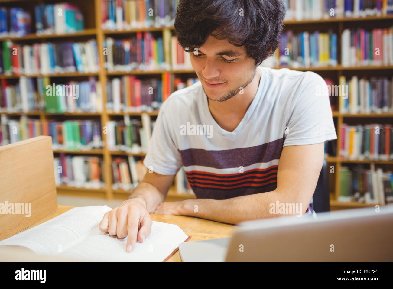 Young student sitting at desk reading a book Stock Photo - Alamy