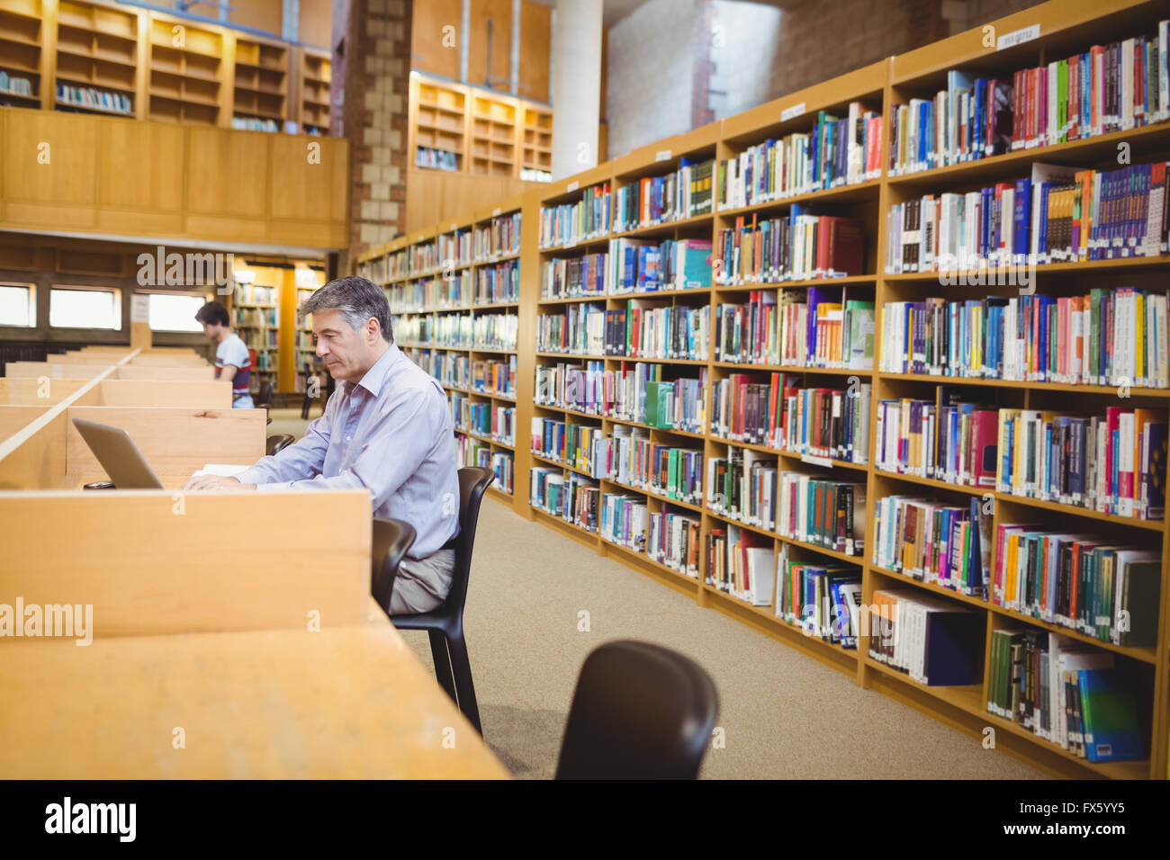 Professor sitting at desk using his laptop Stock Photo - Alamy