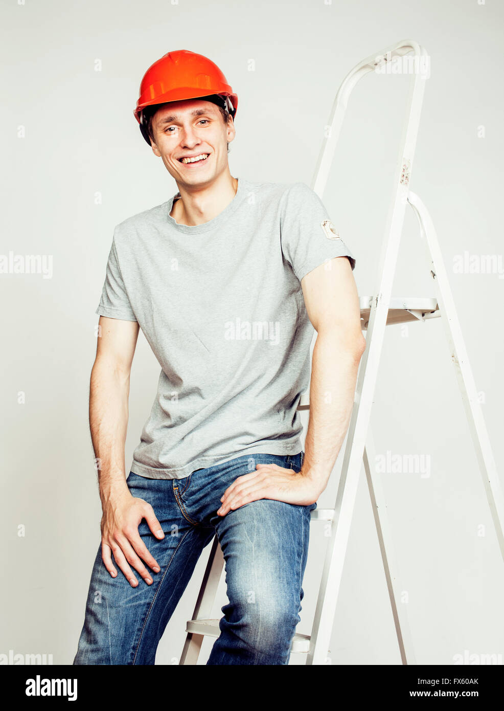 young real hard worker man isolated on white background on ladder ...