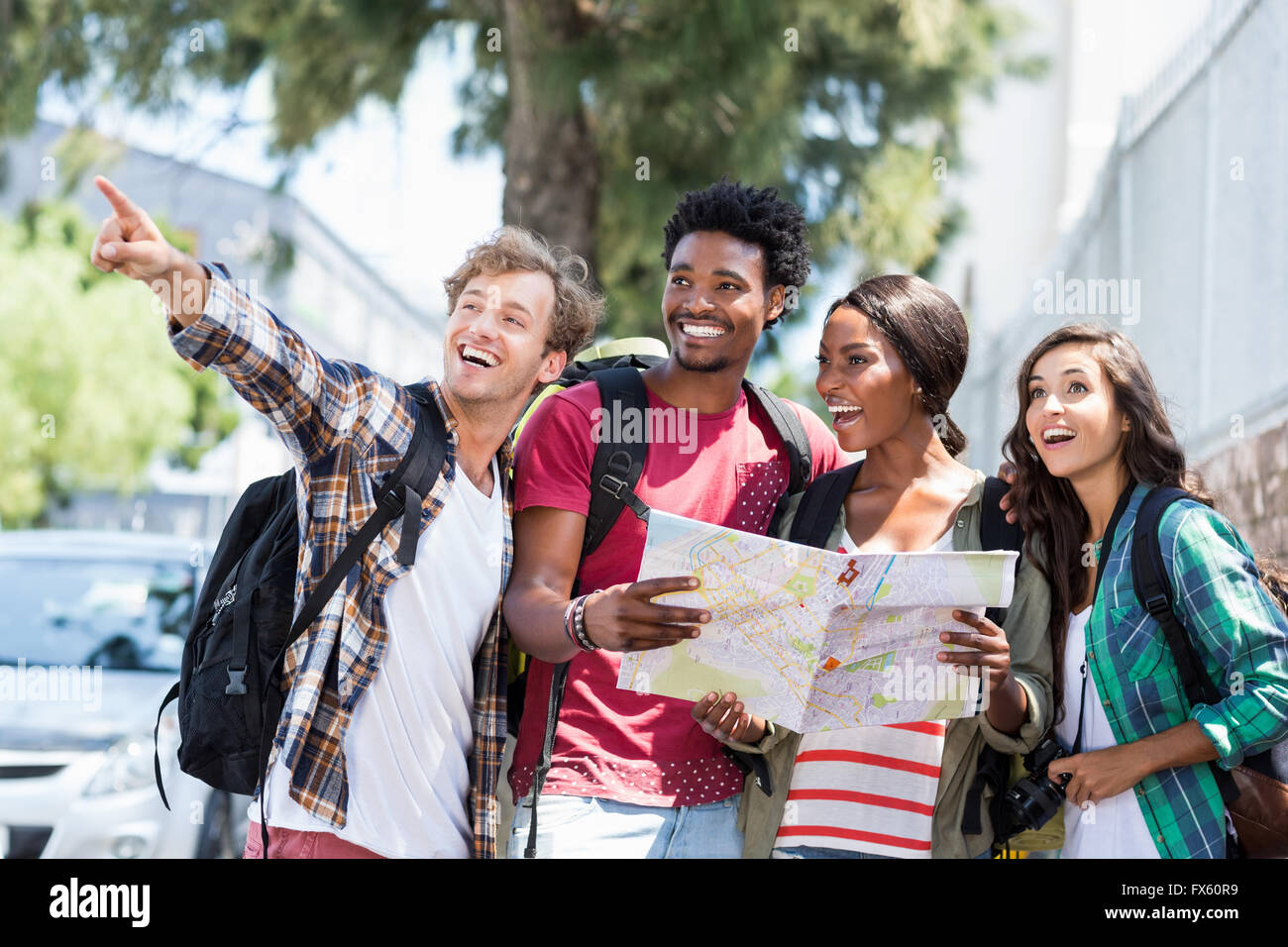 Friends holding map and pointing Stock Photo - Alamy