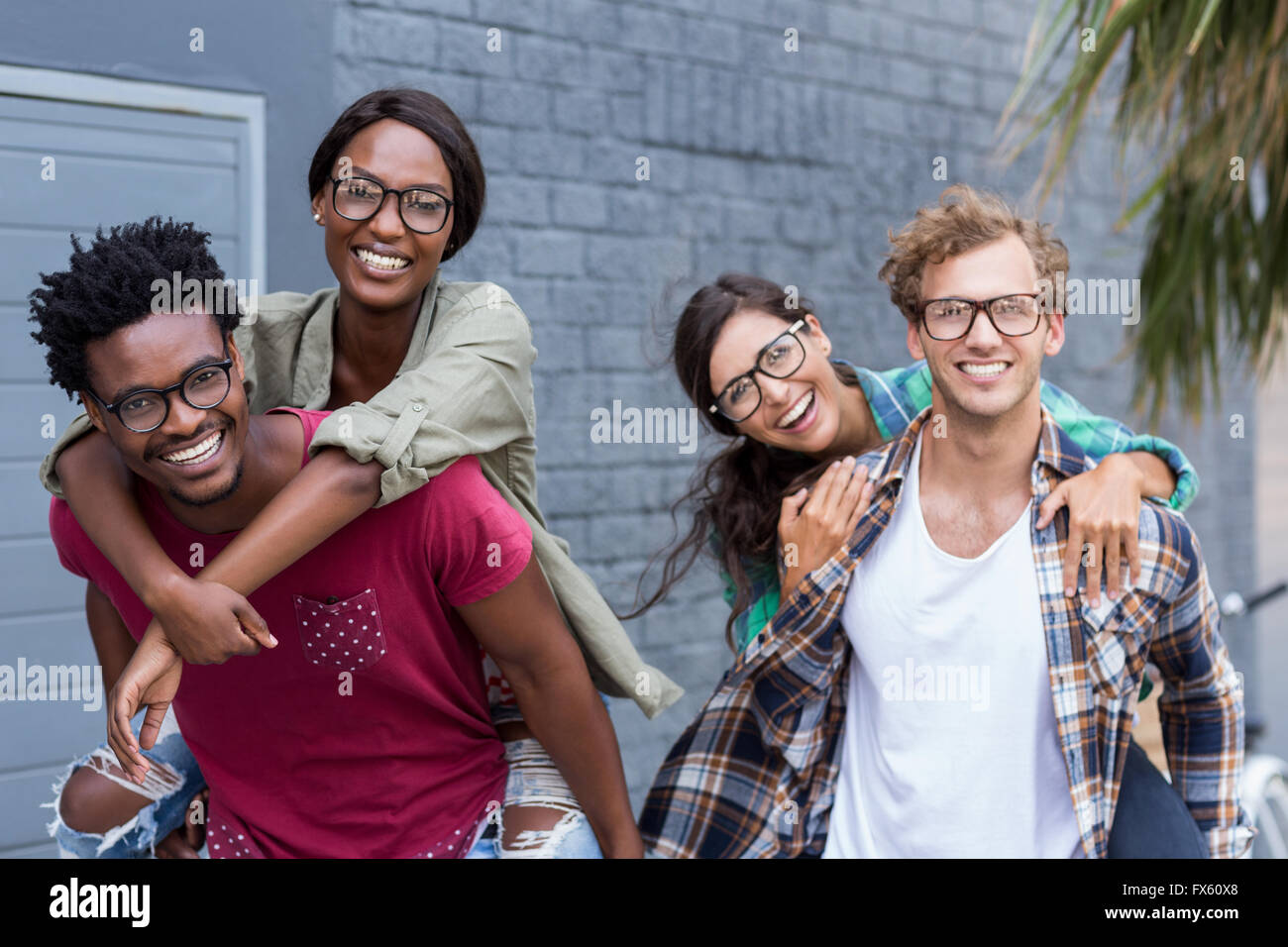 Young men giving piggyback to women Stock Photo - Alamy