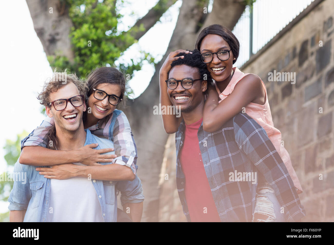 Young men giving piggyback to women Stock Photo - Alamy