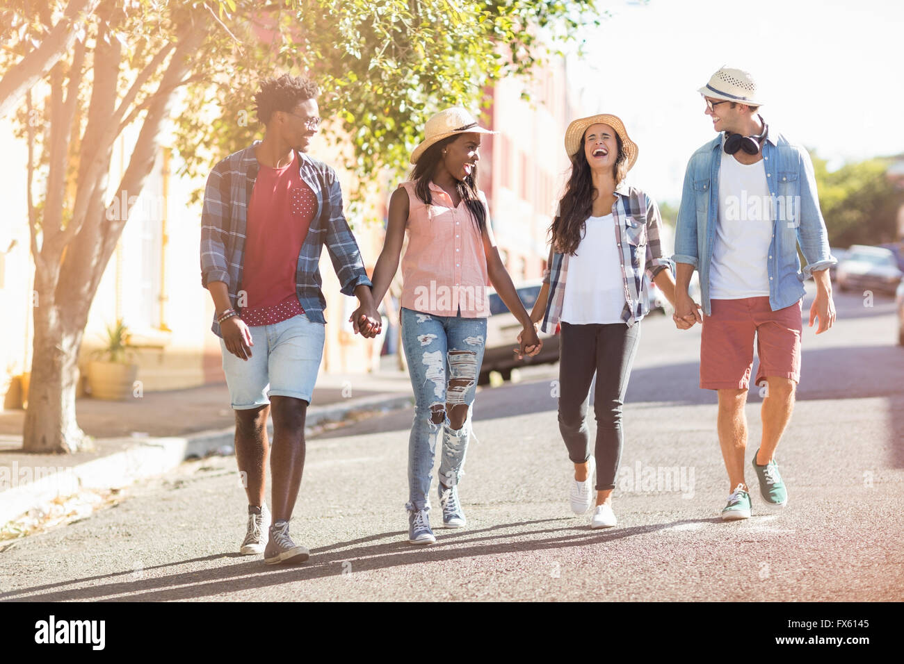Friends walking hand in hand Stock Photo - Alamy