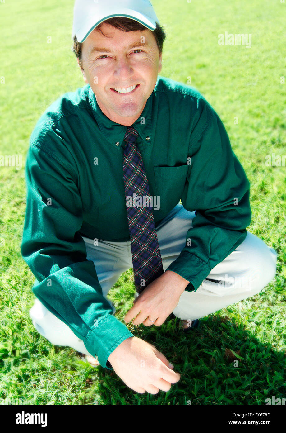 Businessman crouching on grass lawn Stock Photo - Alamy
