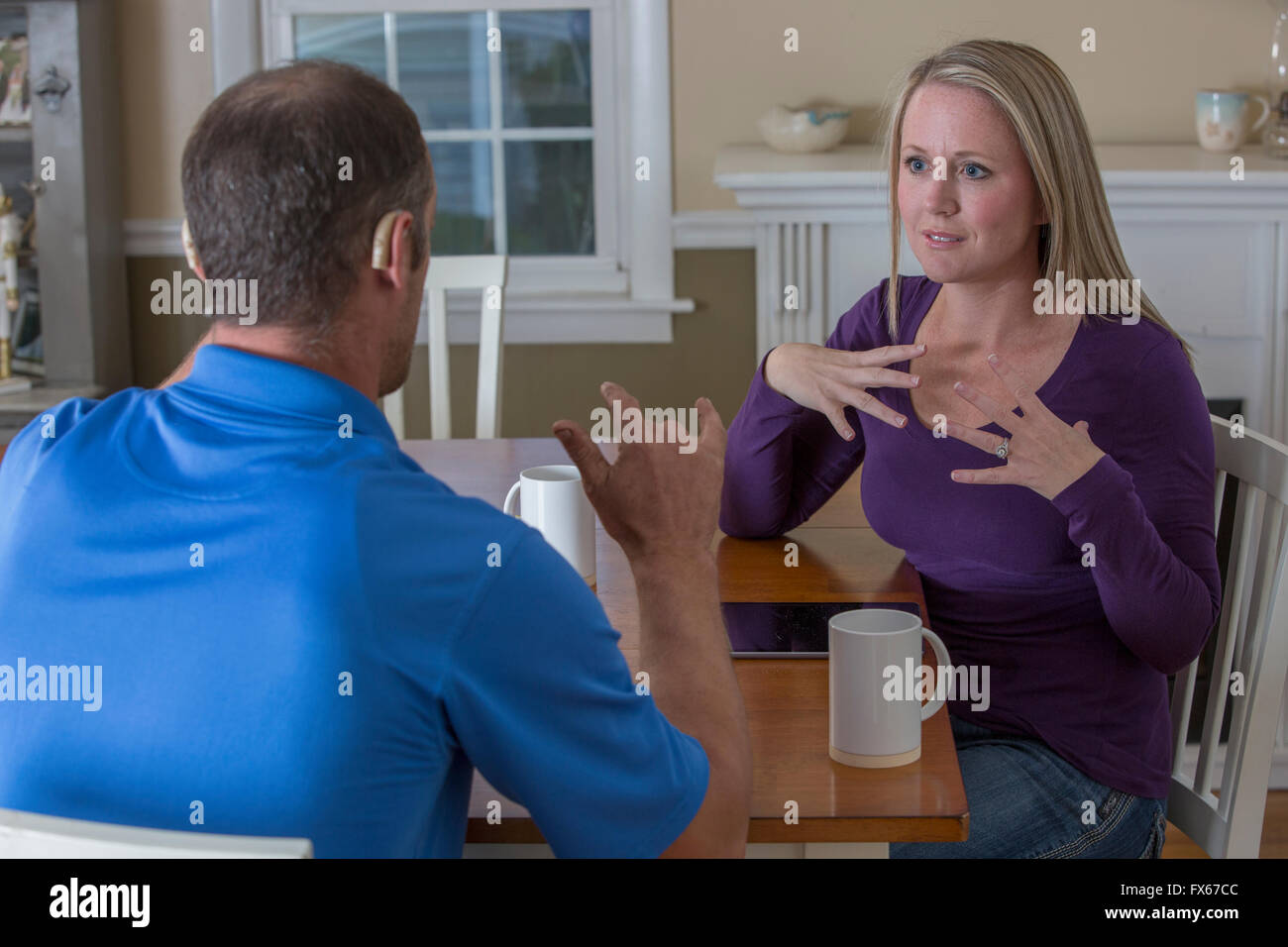 Deaf Caucasian couple signing at dinner table Stock Photo - Alamy