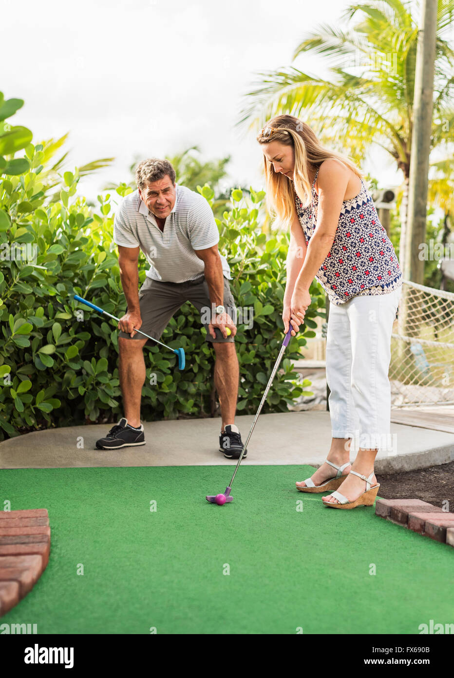 Caucasian couple playing miniature golf Stock Photo - Alamy