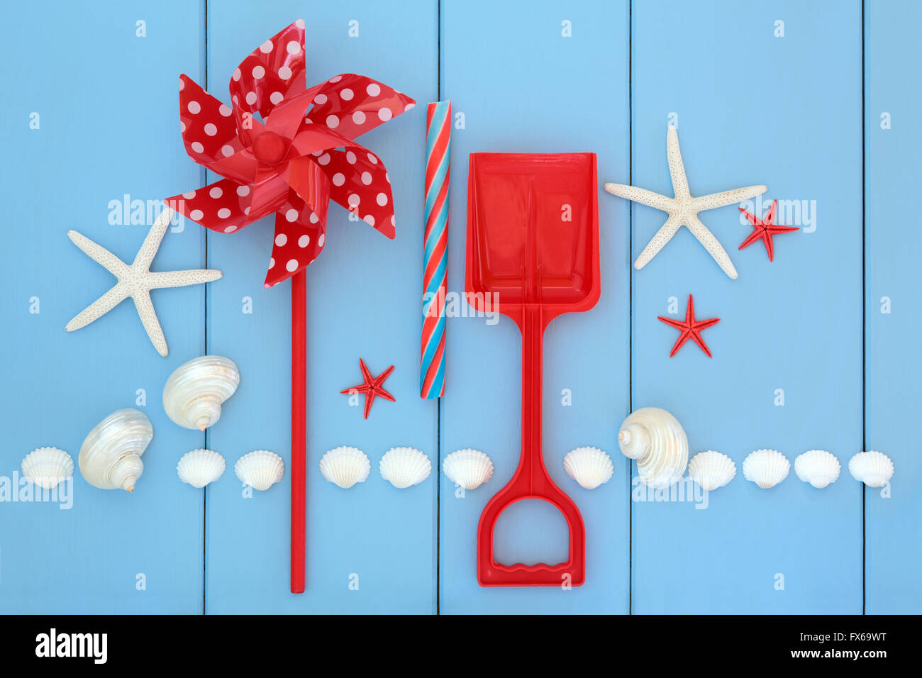 Toy windmill, spade, rock candy and sea shells over wooden blue ...
